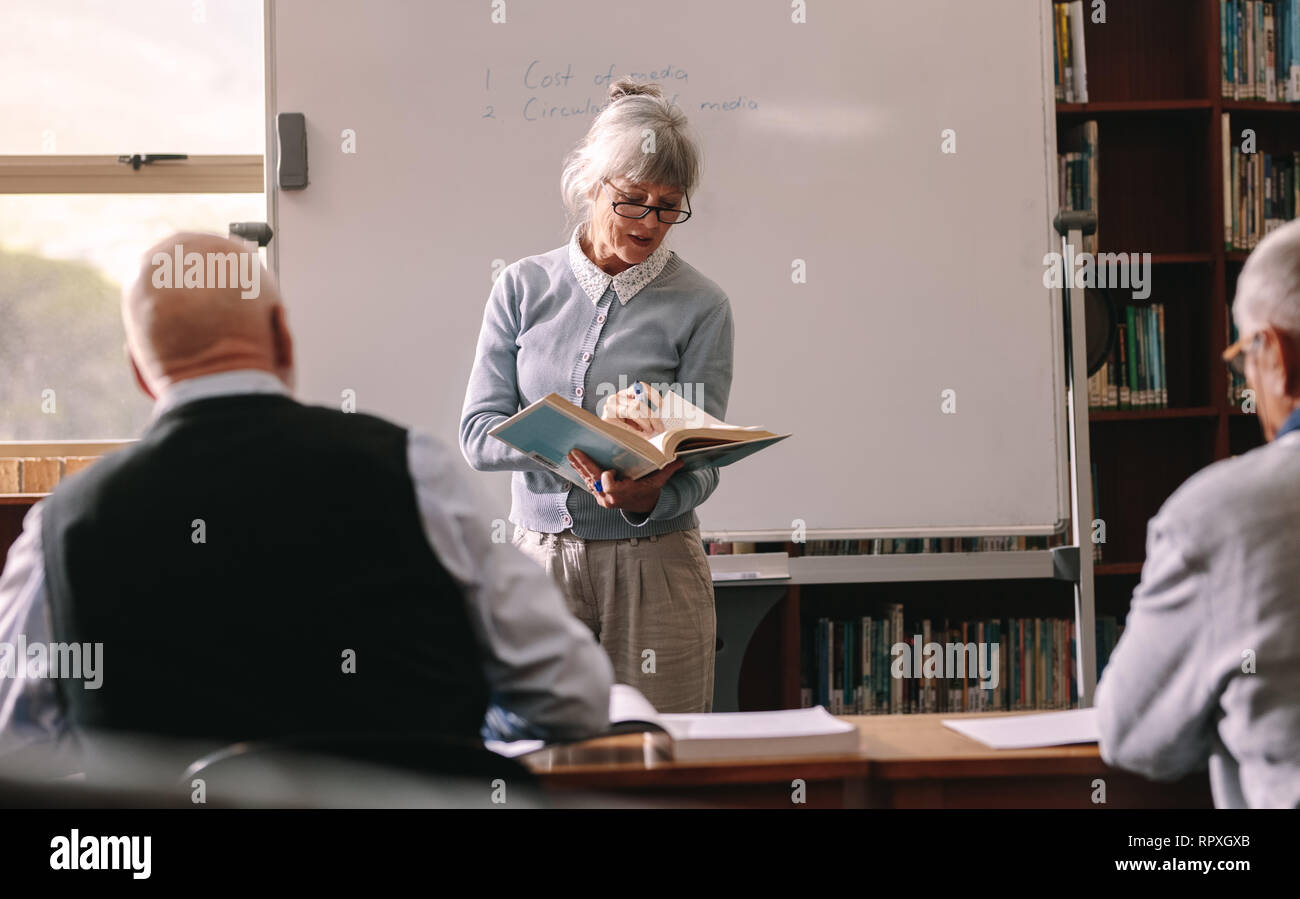 Rear view of two senior men sitting in a university classroom listening ...