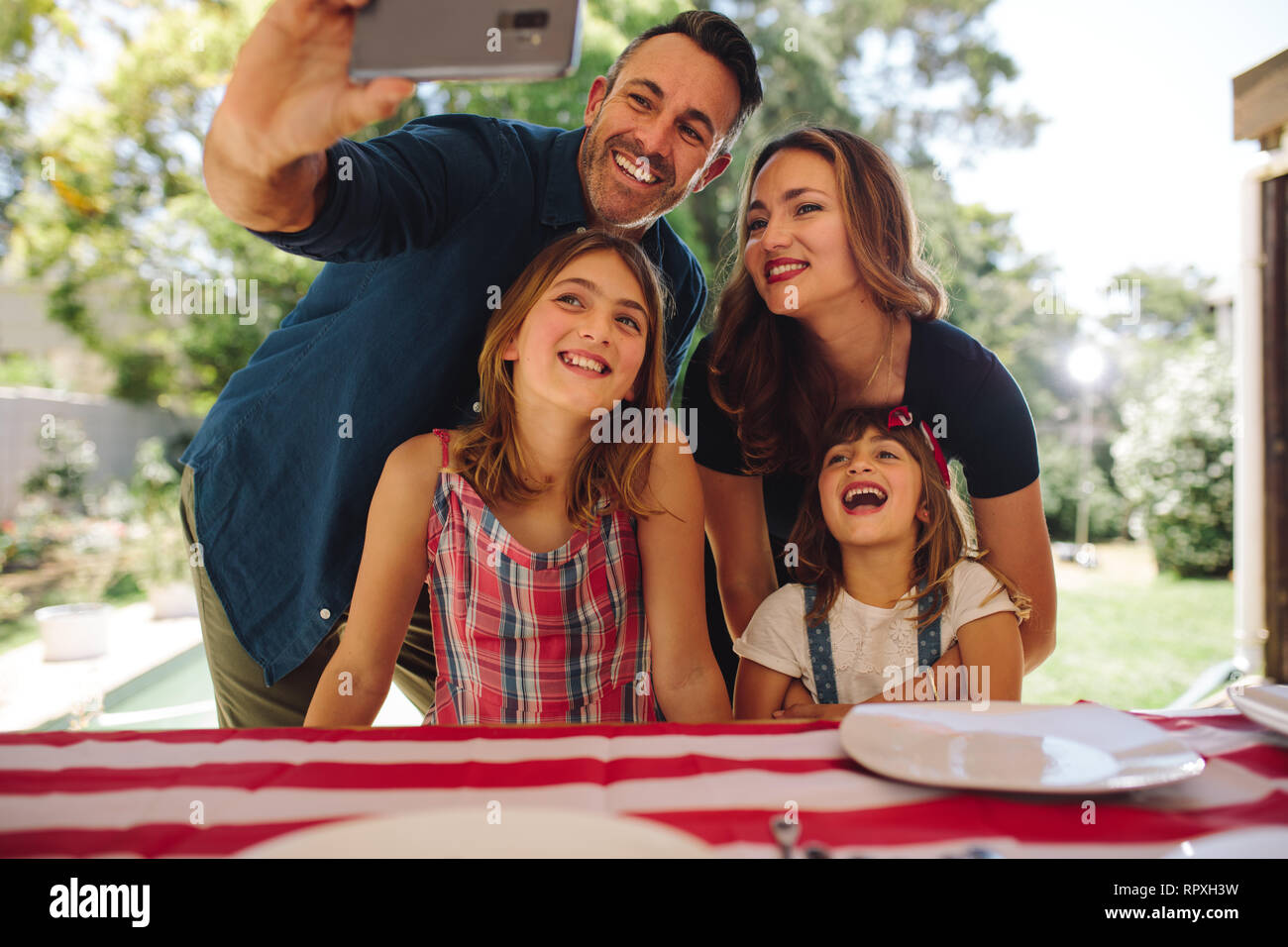 Smiling man taking a selfie with his family members using a mobile ...