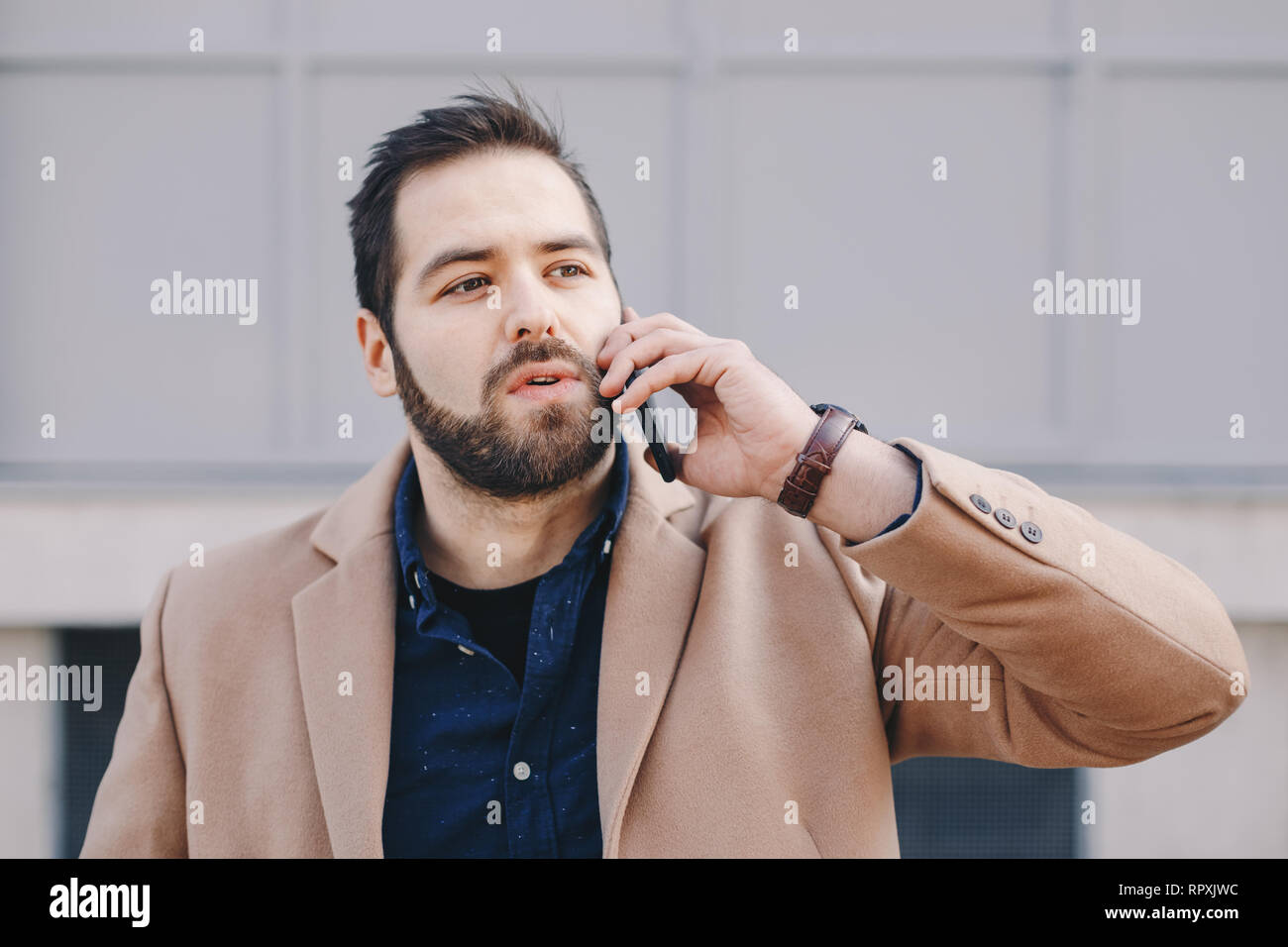 Portrait of an attractive and modern young man chatting on his mobile ...
