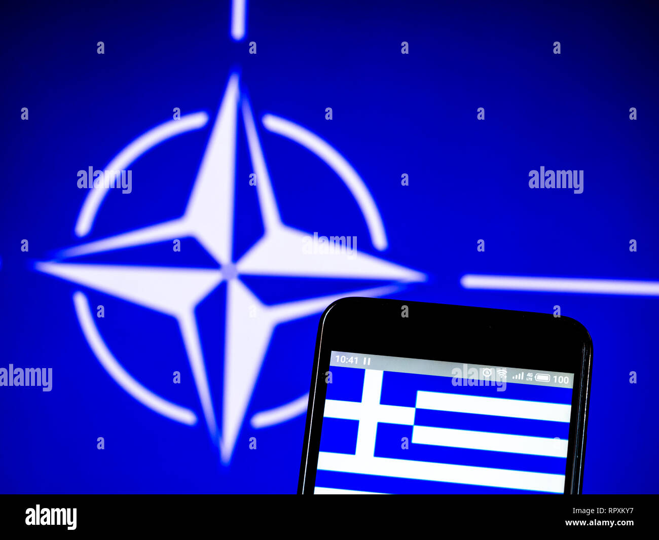 Greece flag on the phone display on the background of the NATO flag ...