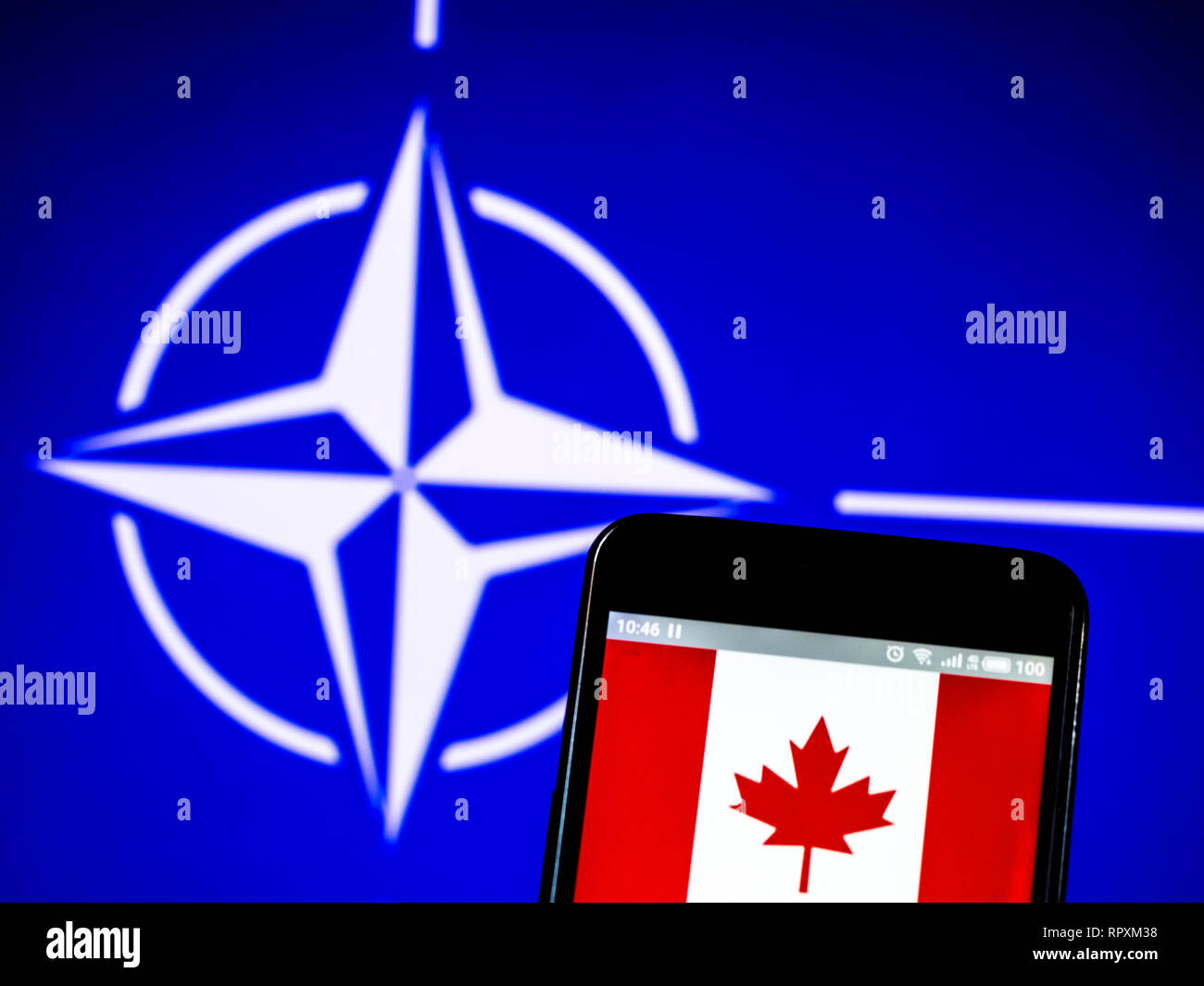 Canada flag on the phone display on the background of the NATO flag ...