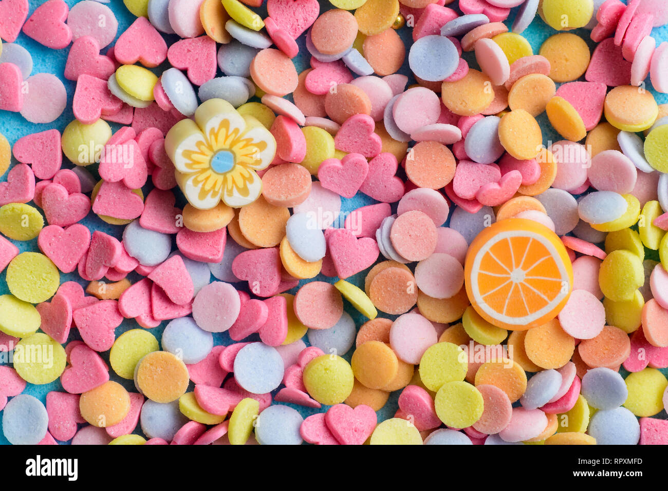 Very small candies of different shapes scattered on bright background ...