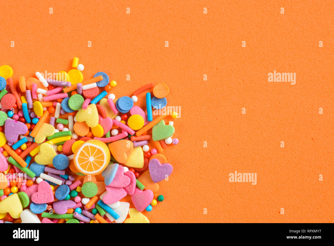 Very small candies of different shapes scattered on bright background ...