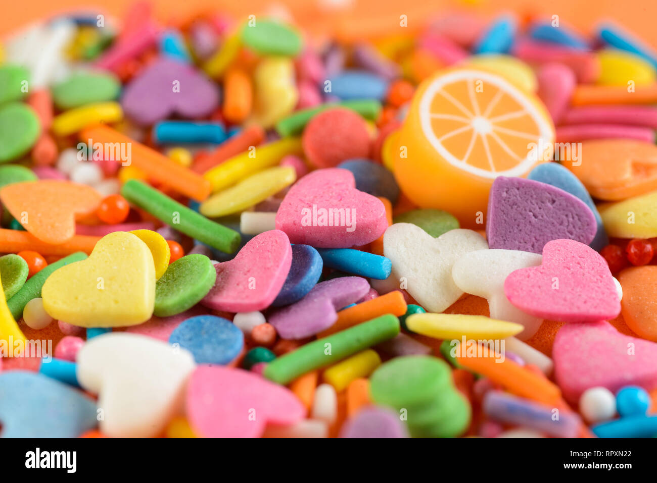 Very small candies of different shapes scattered on bright background ...