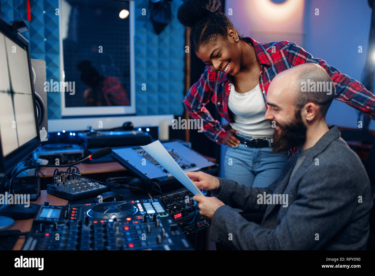 Sound operator and female singer at remote control panel in audio ...