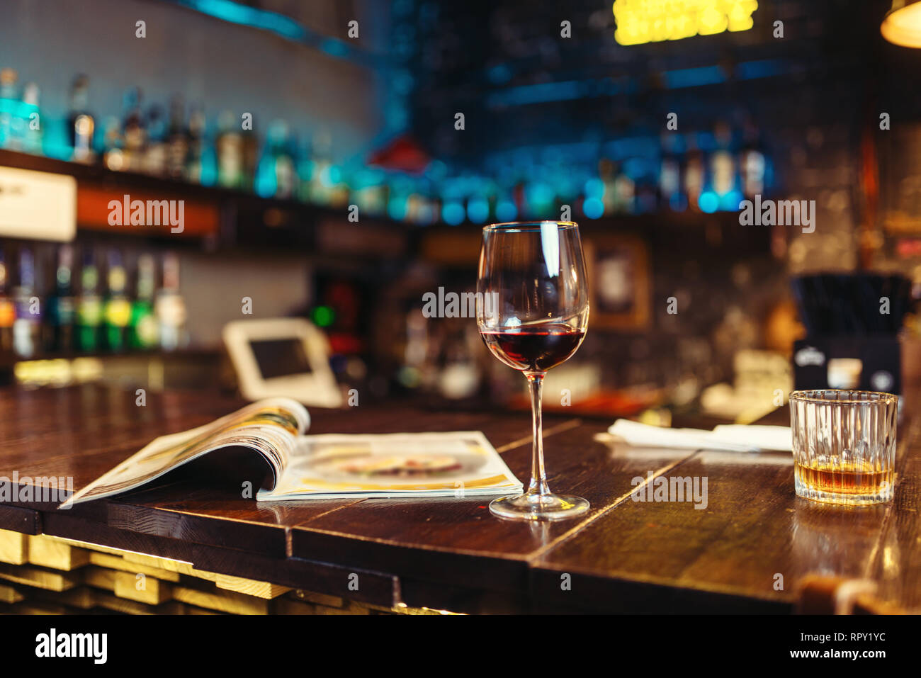 Glass of red wine and opened menu on wooden bar counter, beverages on ...
