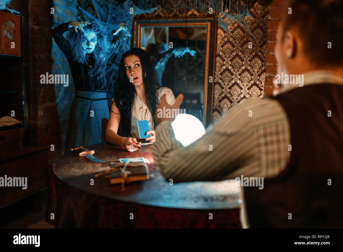Young couple at the table with crystal ball on spiritual seance, scary ...