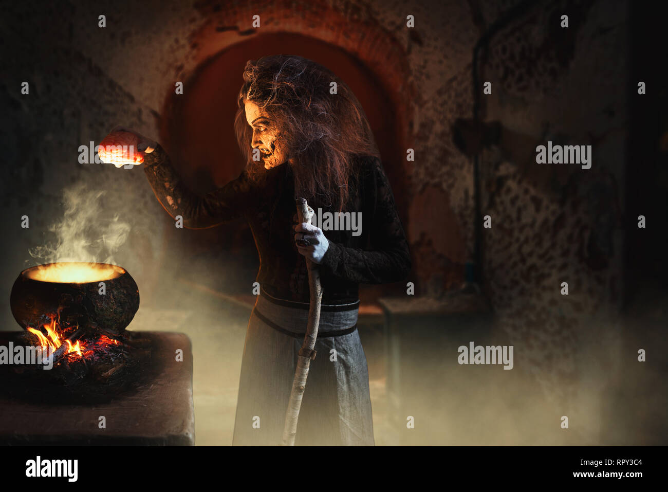 Scary witch reads spell over the pot with human body parts, dark powers ...