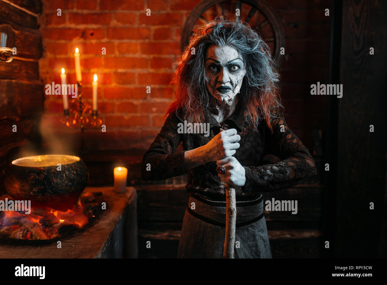 Scary witch on spiritual seance, cooking, witchcraft with candles ...