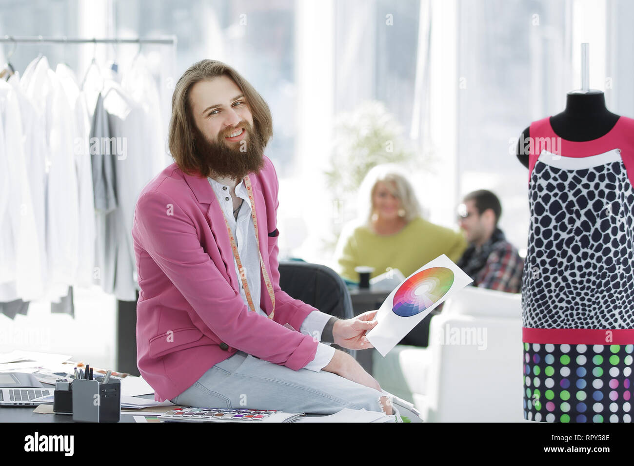 portrait of a clothing designer sitting on a Desk in the Studio Stock ...