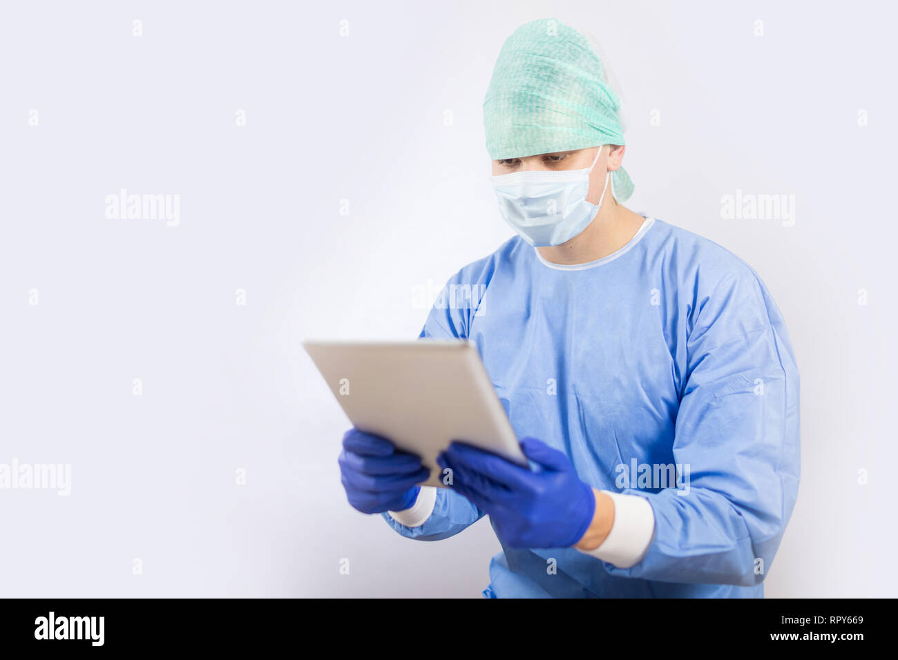 Surgeon Doctor In Sterile Gloves Preparing For Operation Using Tablet
