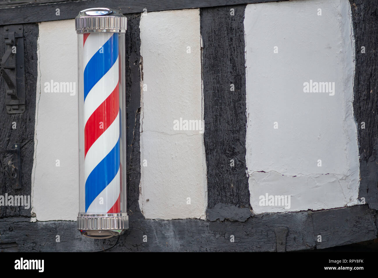 red white and blue barbers pole on ancient timber wall in the UK Stock ...
