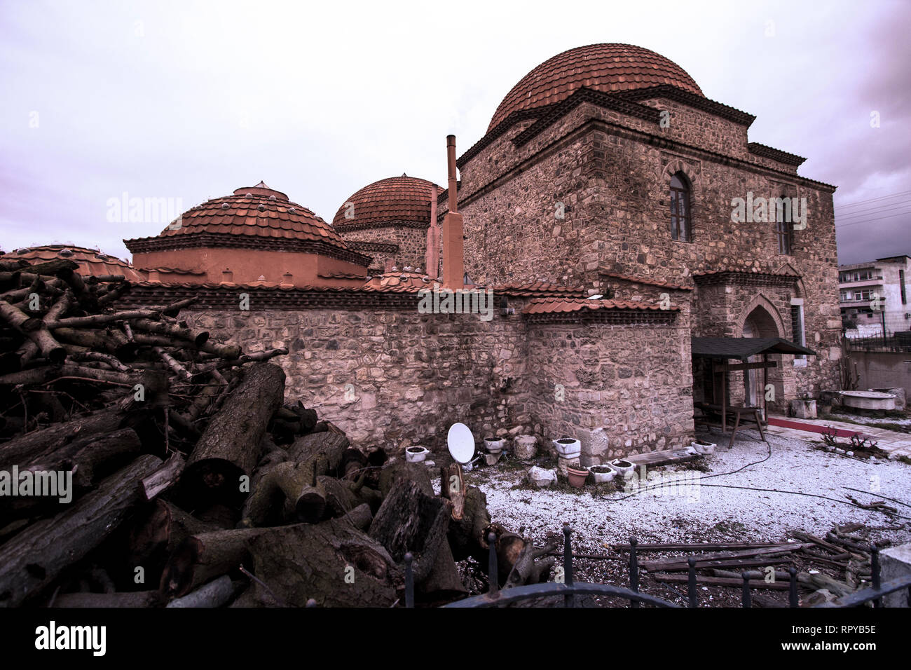 A Turkish bath with a large pile of wood in the front yard waiting to ...