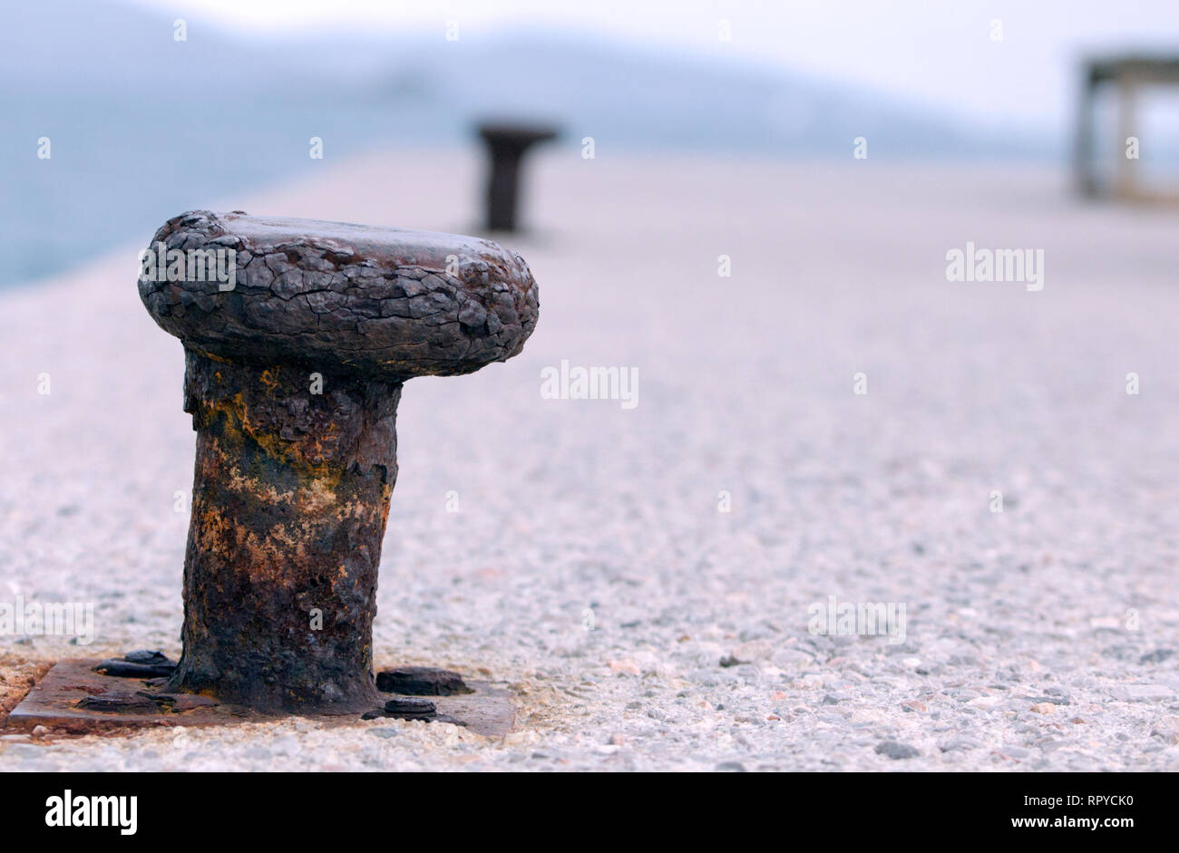 Close-up profile of worn-out rusted bollard in perspective with another ...
