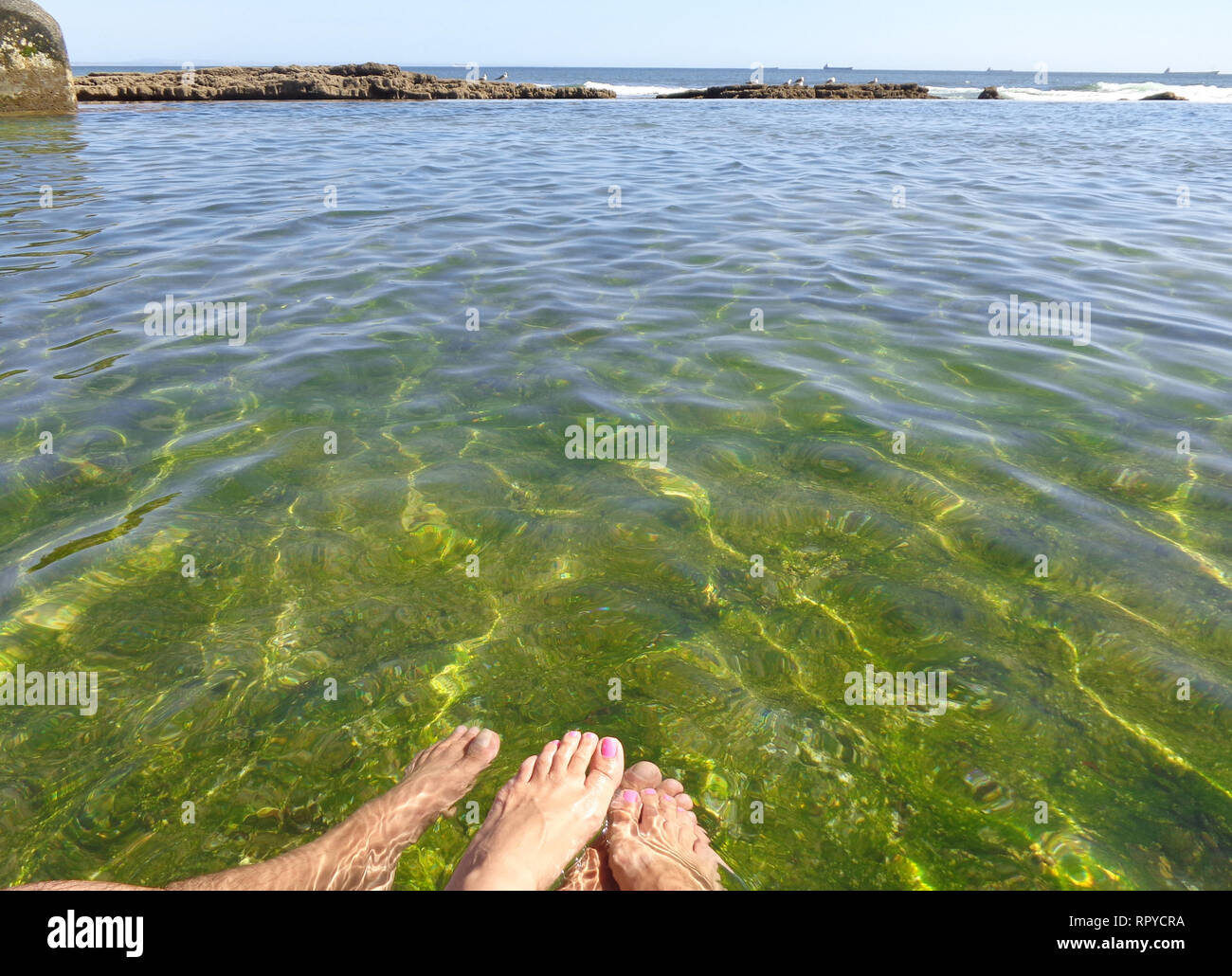 Feet of a couple in crystal clear sea water with depth of field with ...