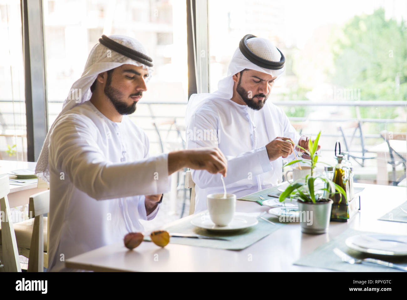 Group of middle eastern men wearing kandora bonding in a cafè restarant ...