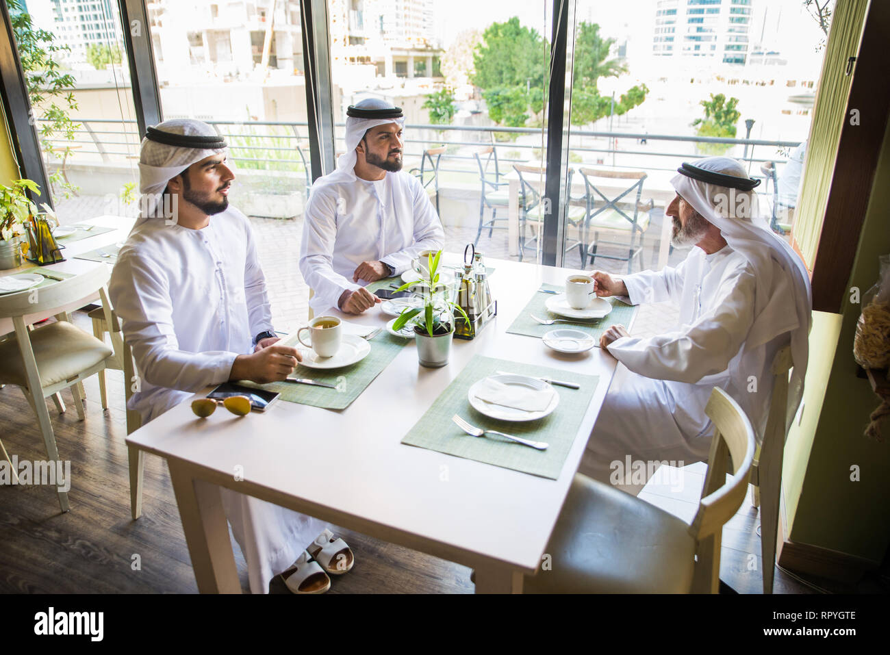 Group of middle eastern men wearing kandora bonding in a cafè restarant ...