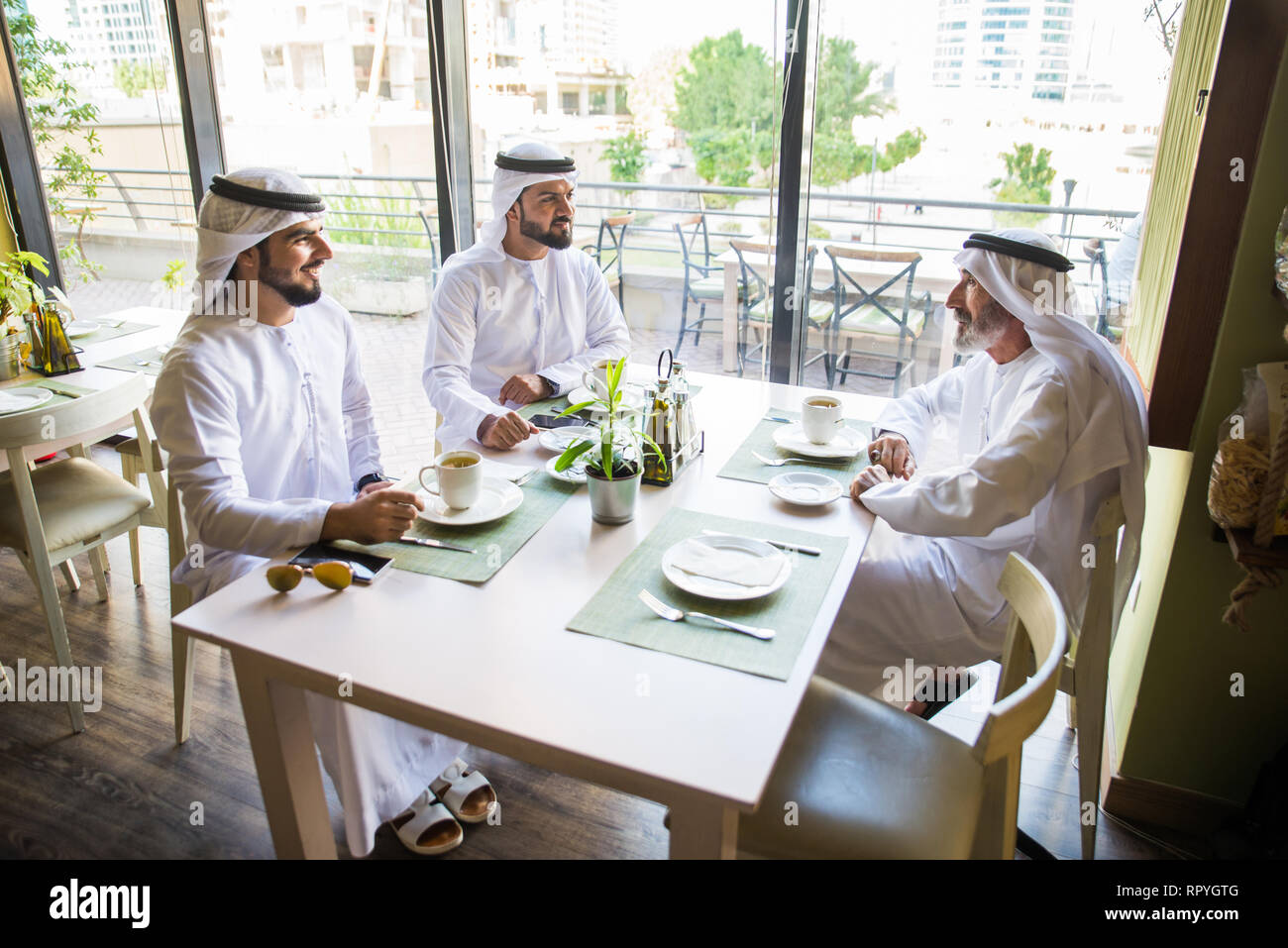Group of middle eastern men wearing kandora bonding in a cafè restarant ...