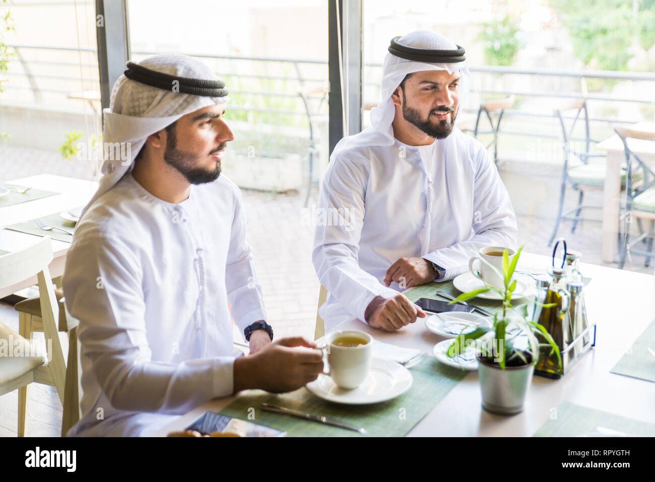 Group of middle eastern men wearing kandora bonding in a cafè restarant ...
