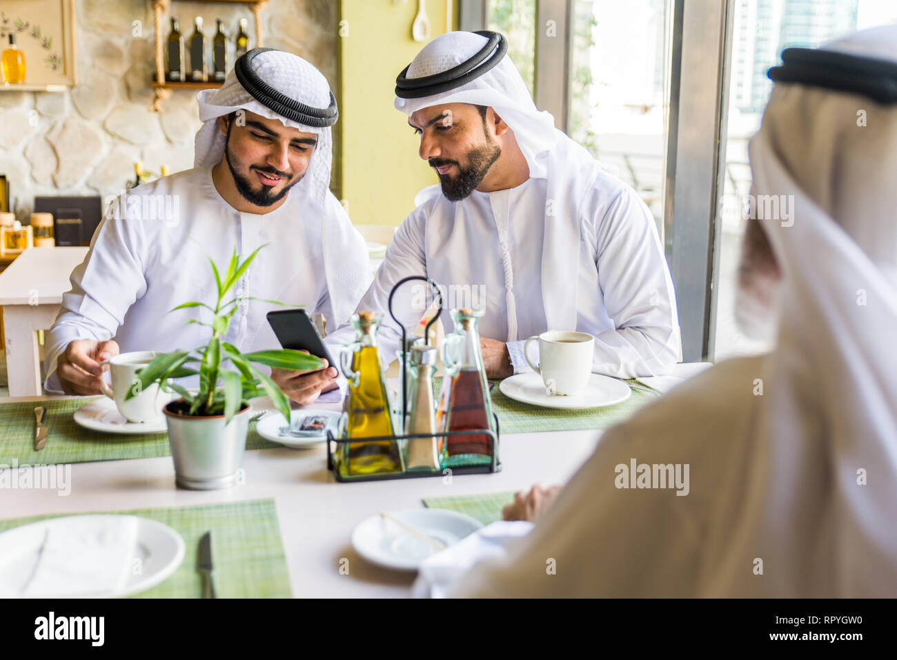 Group of middle eastern men wearing kandora bonding in a cafè restarant ...