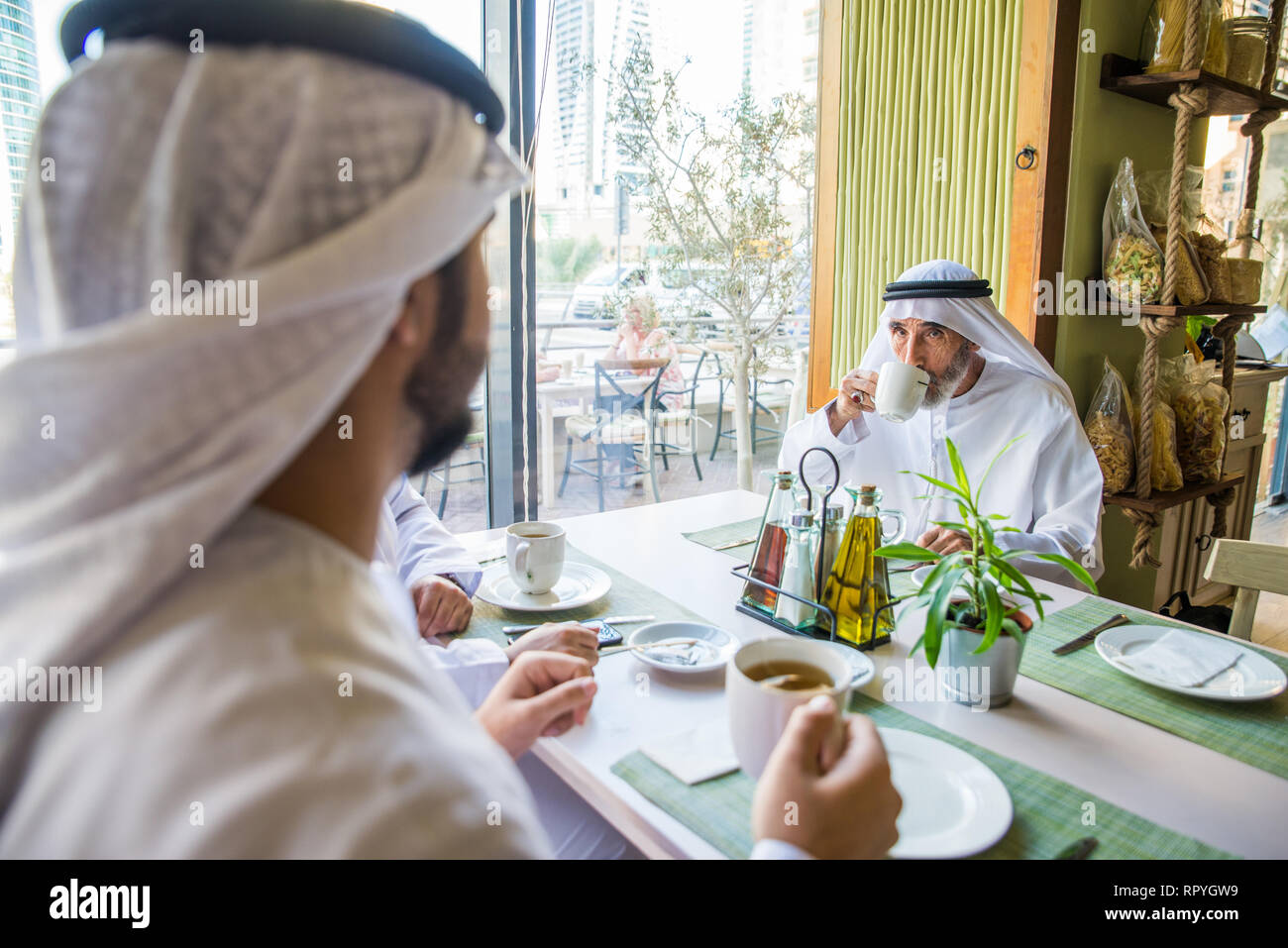 Group of middle eastern men wearing kandora bonding in a cafè restarant ...