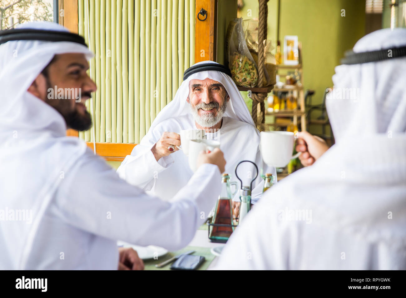 Group of middle eastern men wearing kandora bonding in a cafè restarant ...
