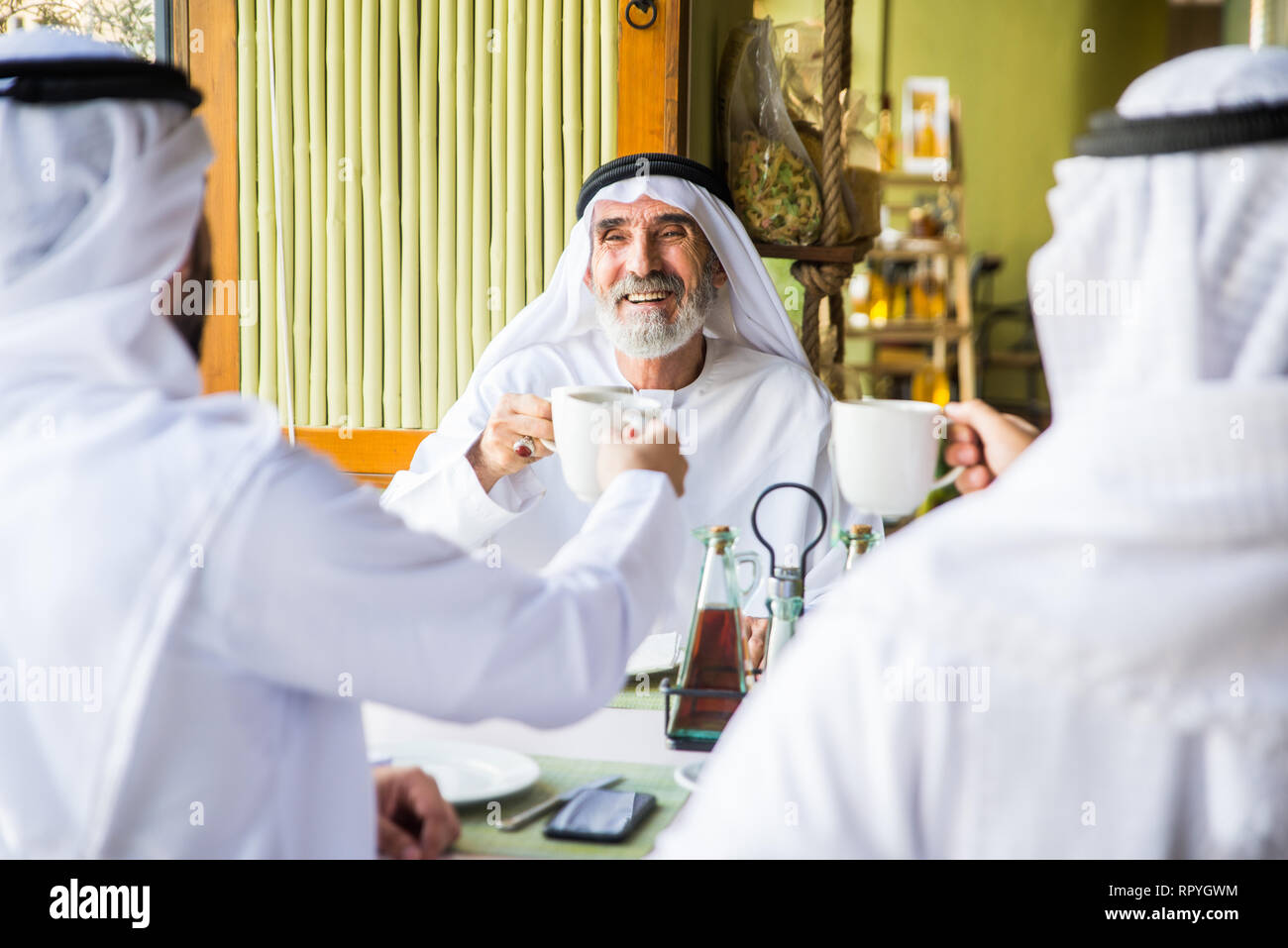 Group of middle eastern men wearing kandora bonding in a cafè restarant ...