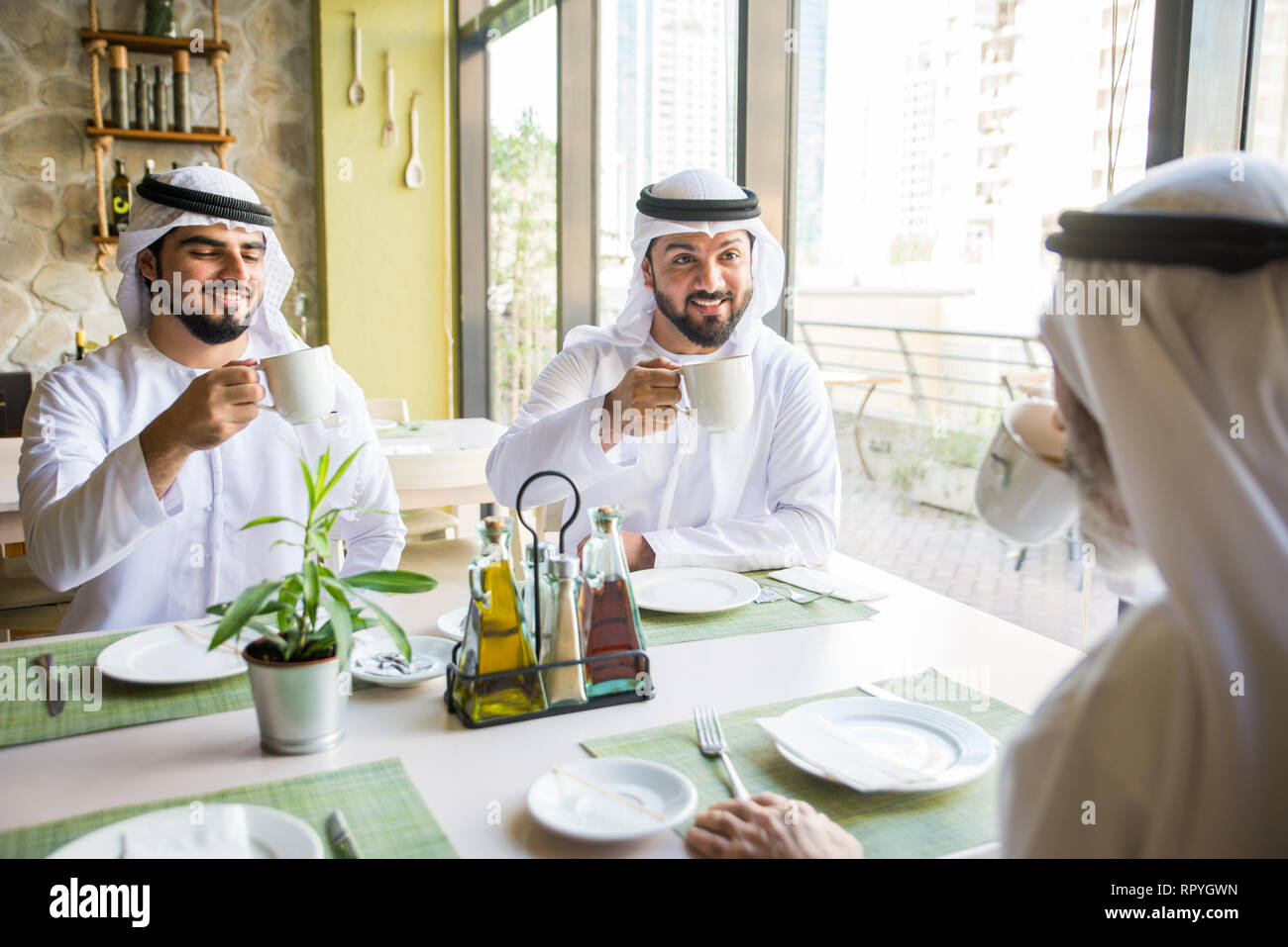 Group of middle eastern men wearing kandora bonding in a cafè restarant ...