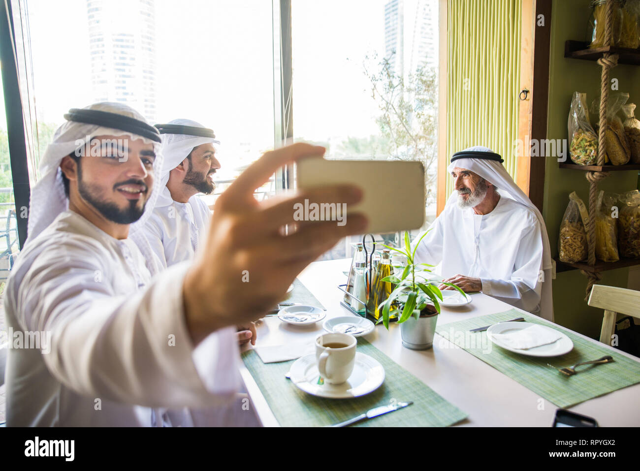 Group of middle eastern men wearing kandora bonding in a cafè restarant ...