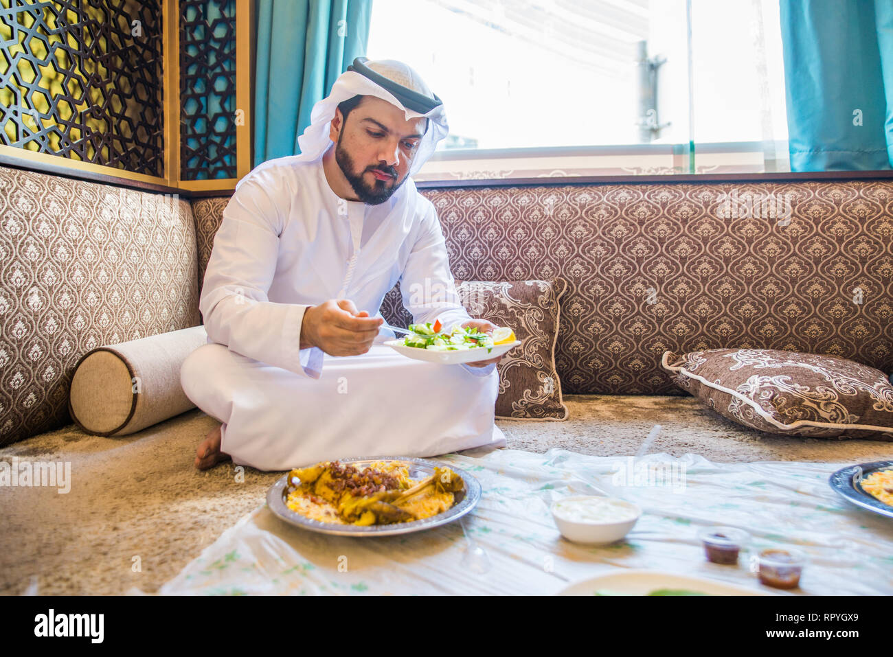 Middle eastern man wearing kandora eating in a cafè restarant in Dubai ...