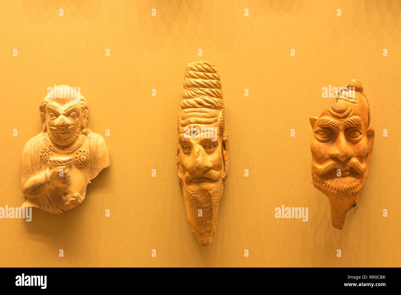 Several ancient head casts are suspended on the surface of a pink shade ...