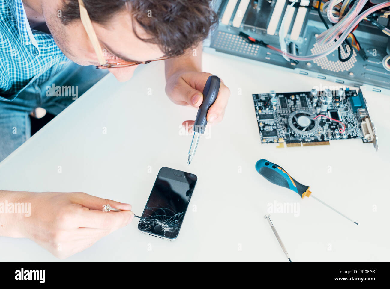 Repairman changing broken smartphone screen in service center Stock ...