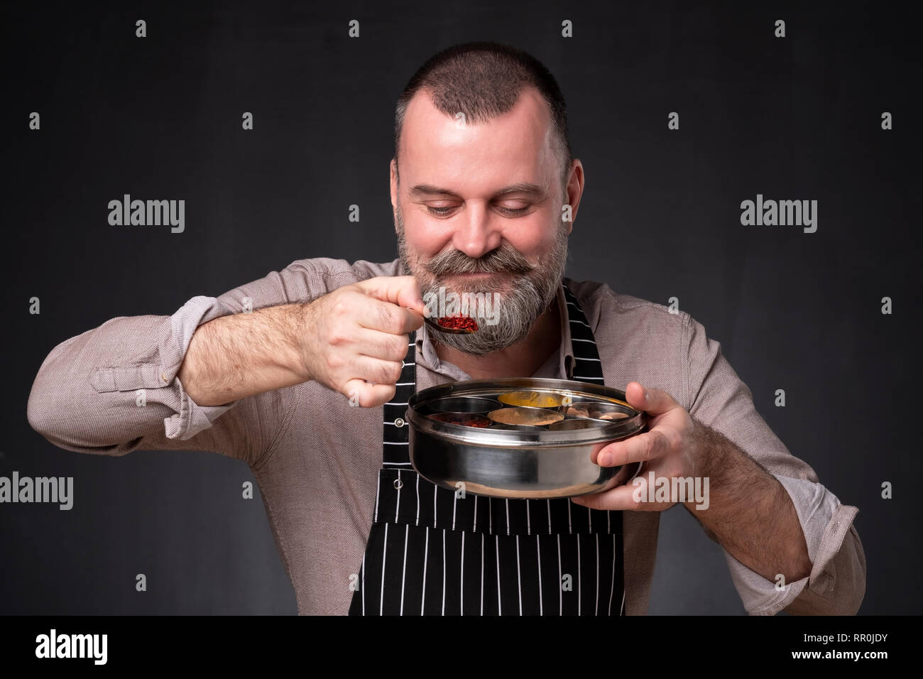 Bearded male chef showing different spices he uses. Secret of delicious ...