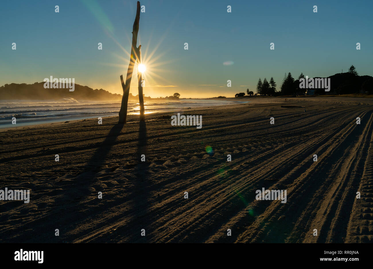 Tracks from beach grooming leading away towards sunrise with sun burst ...