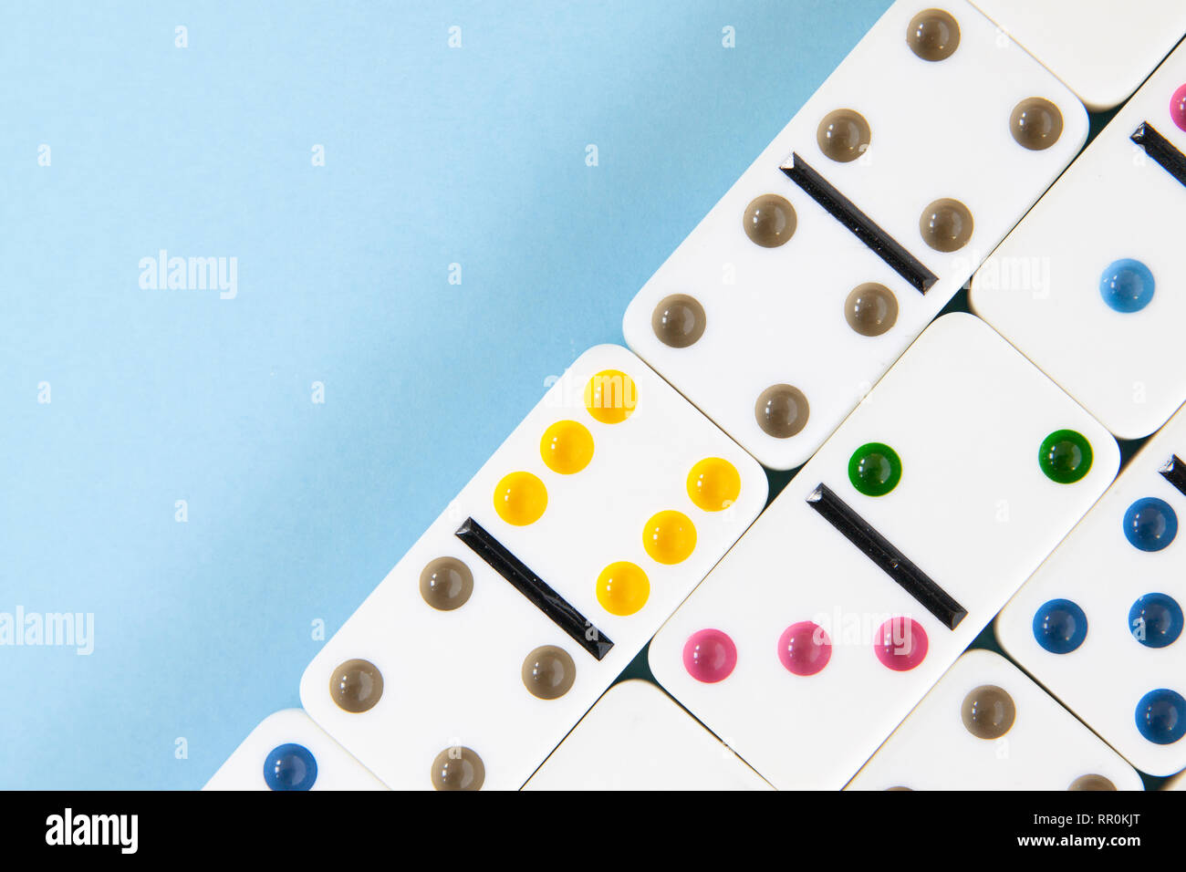 Overhead closeup of white dominoes with brightly colored dots on a blue ...
