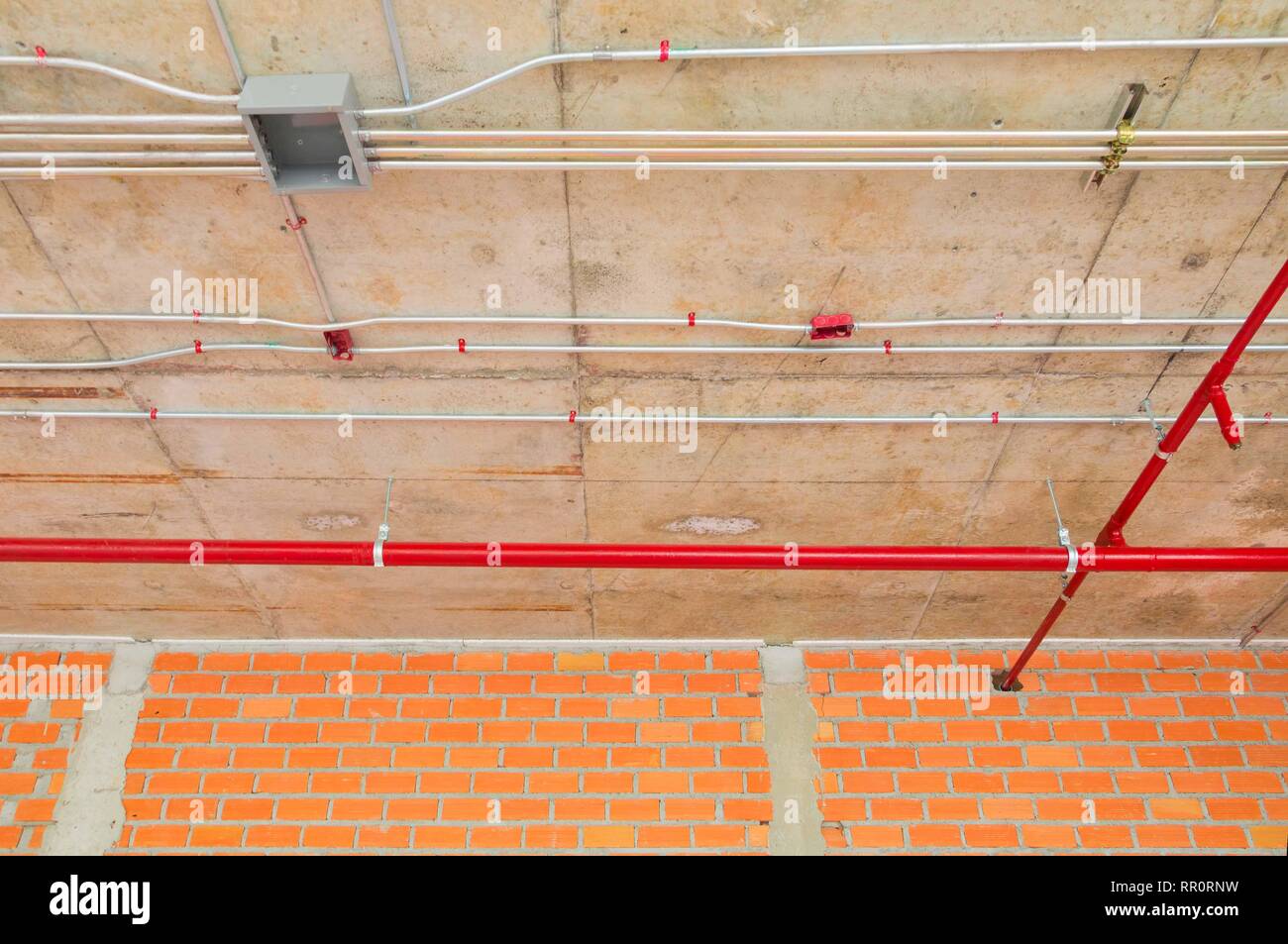 Metal pipes in Construction and fire sprinkler on red pipe are hanging ...