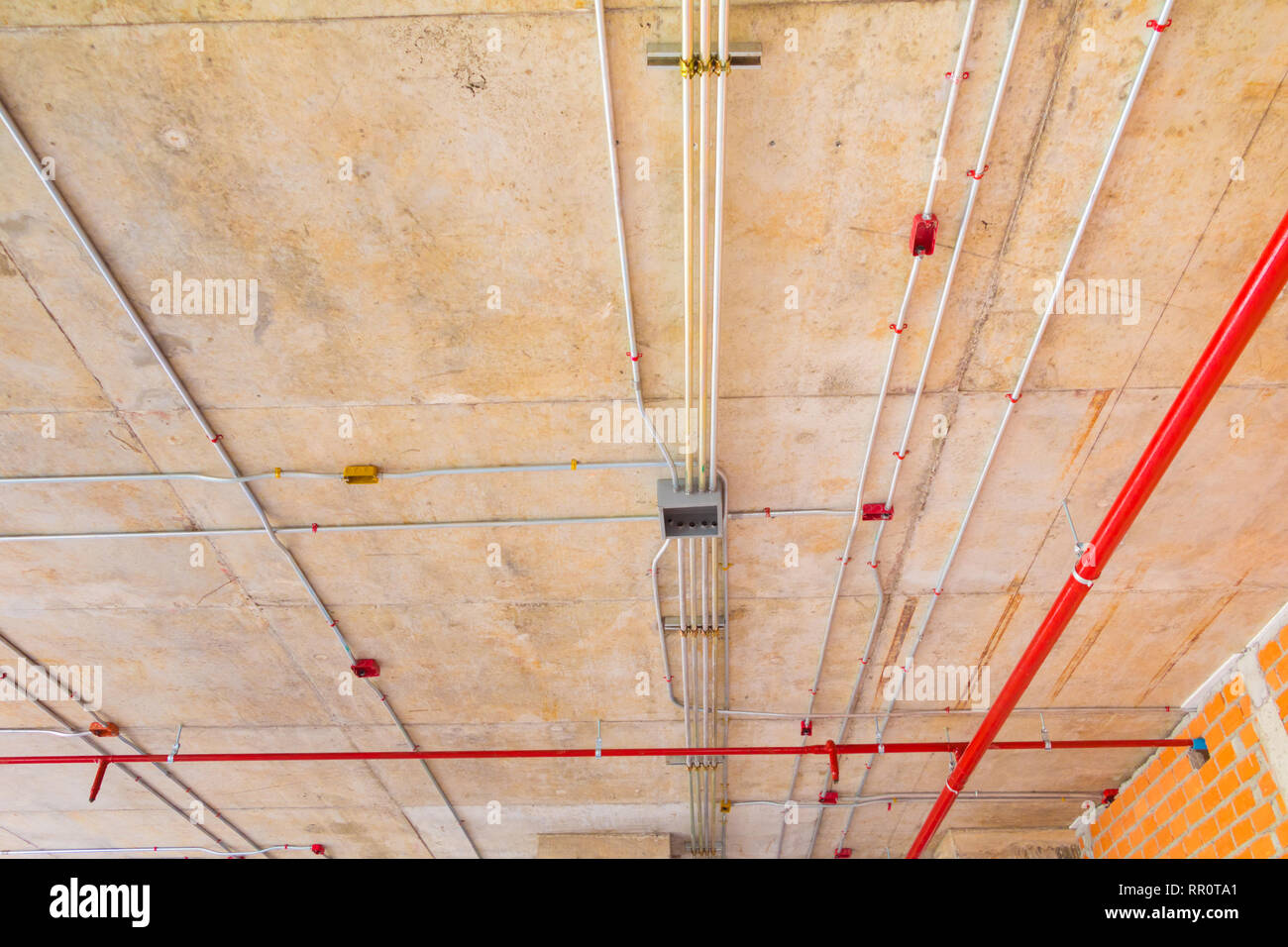 Metal pipes in Construction and fire sprinkler on red pipe are hanging ...