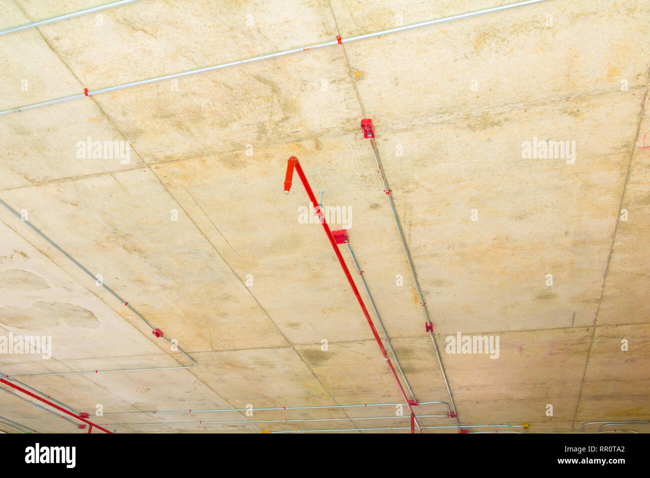 Metal pipes in Construction and fire sprinkler on red pipe are hanging ...