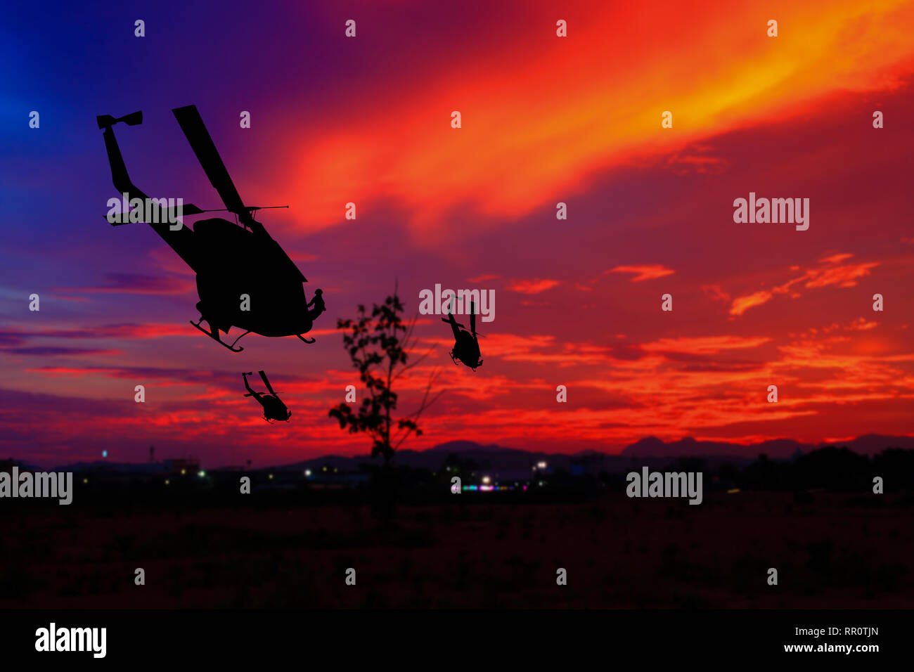 soldier silhouette in rappelling climb down from helicopter on sunset ...