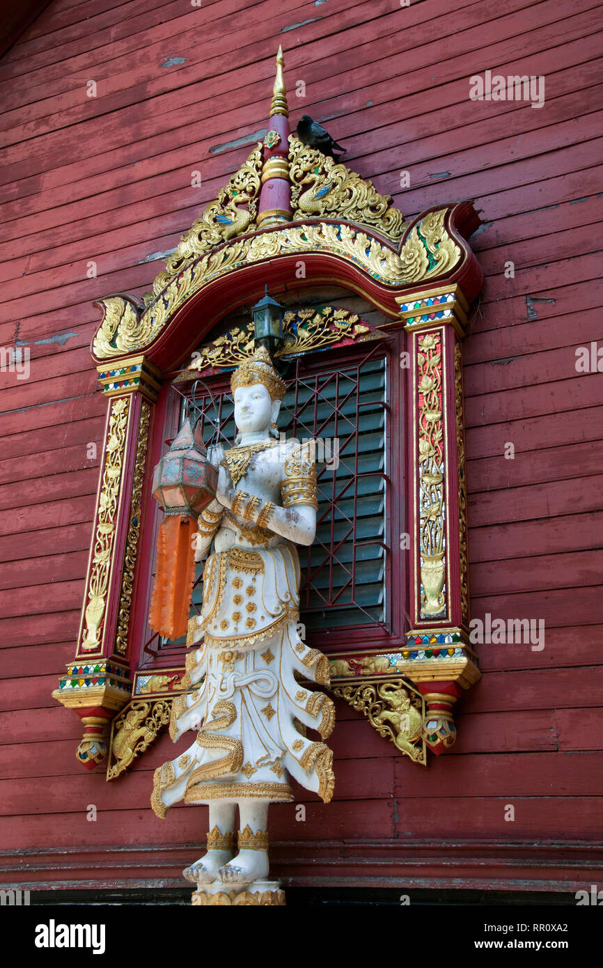 Chiang Rai Thailand, statue holding lantern in-front of carved window ...