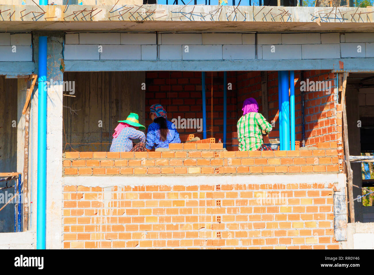 Female worker bricklayer laying brick a wall construction in industrial ...