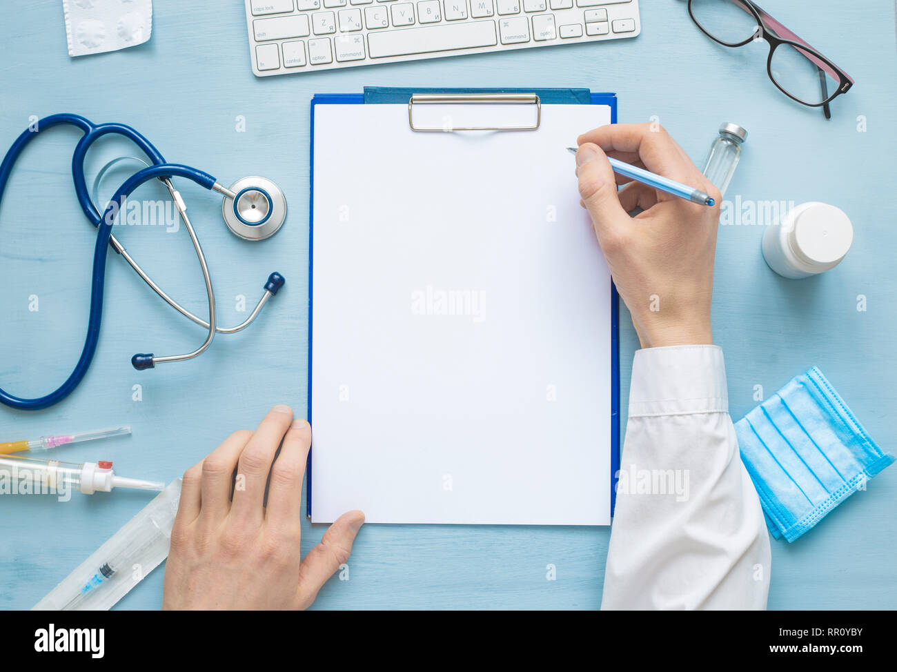 doctor’s hands writing down a prescription or medical report on a blank ...
