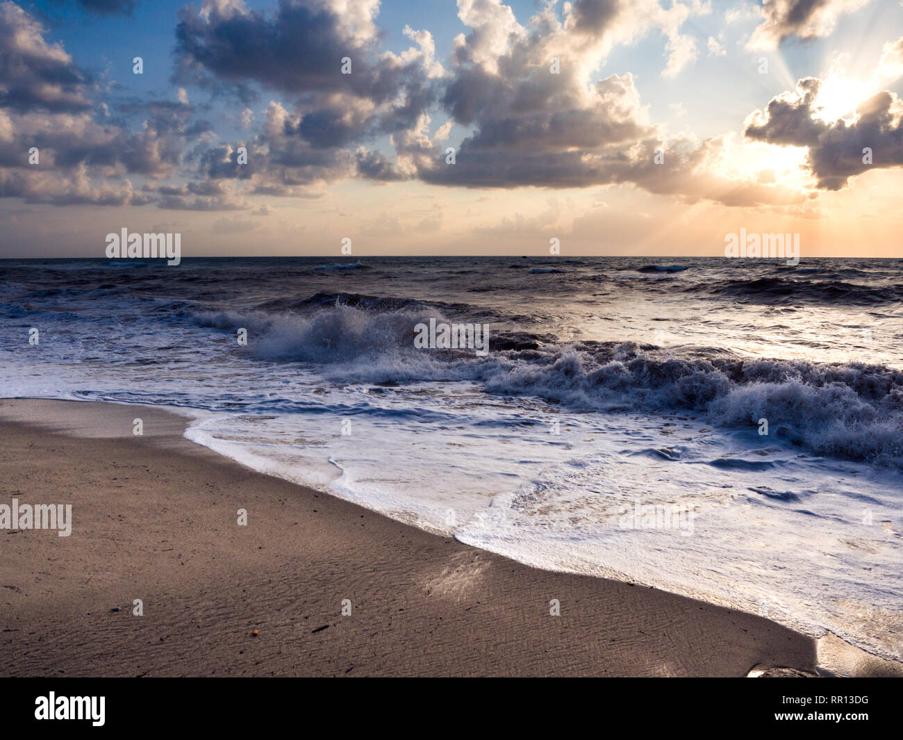 Sunset beach with rough seas and crashing waves Stock Photo - Alamy