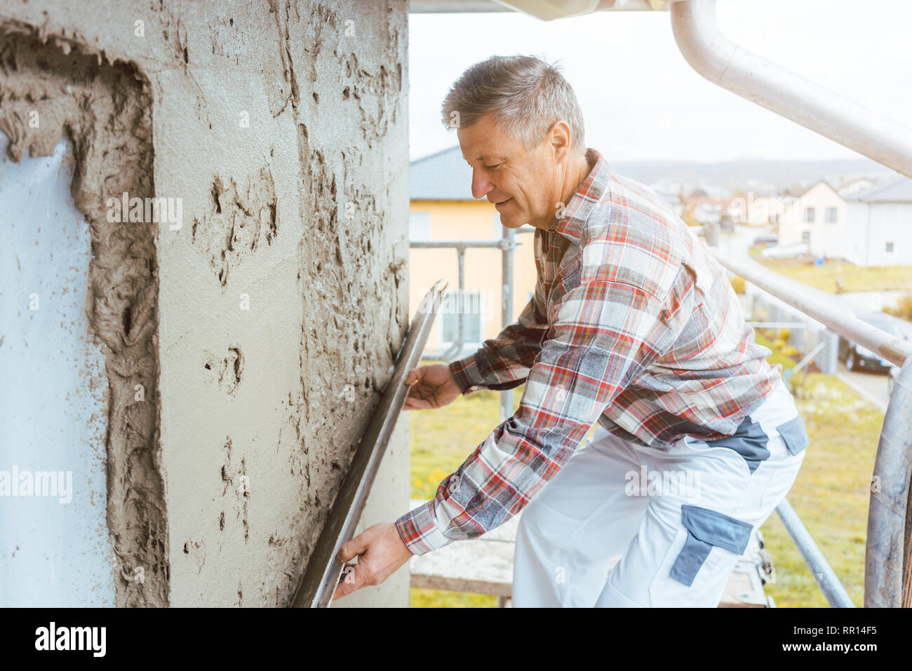 Plasterer smoothing plaster on a facade Stock Photo - Alamy