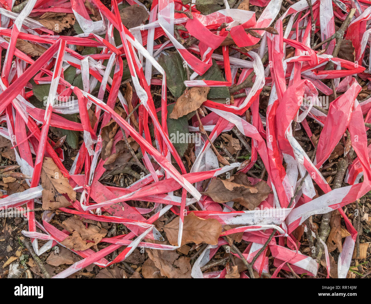 Pile of abandoned red and white barrier warning tape left on the ground ...