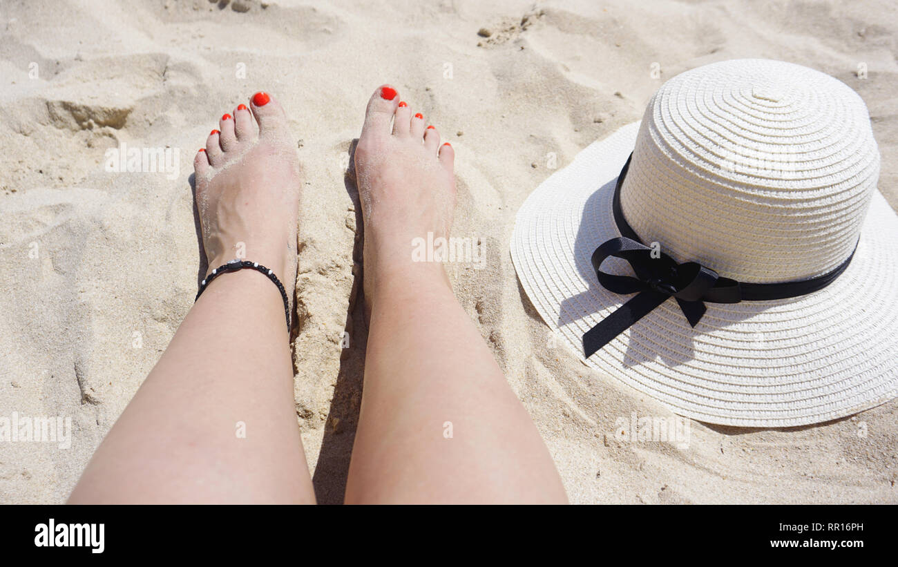 Summer holiday fashion concept - tanning woman legs and sun hat at the ...