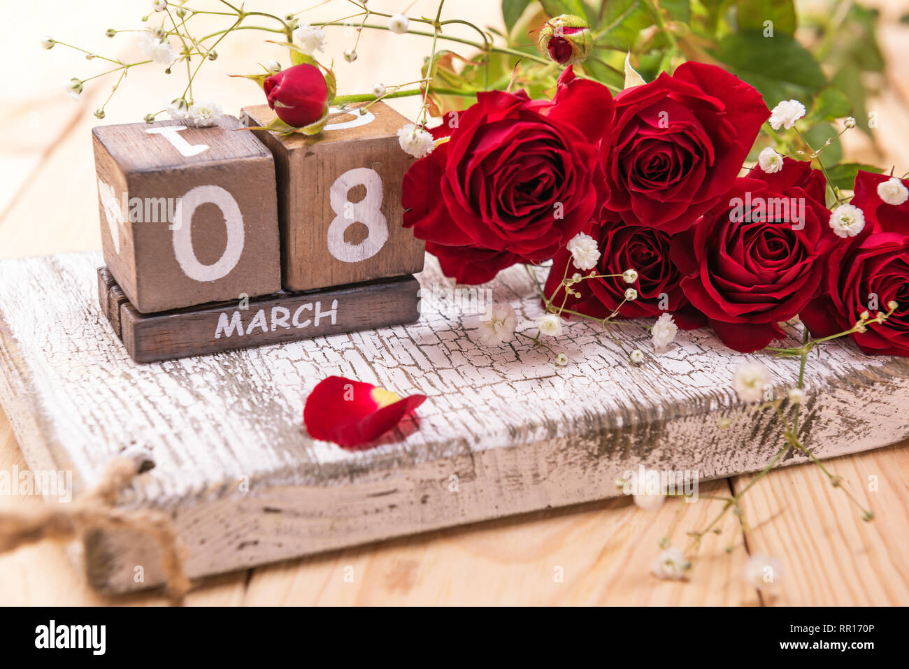 Wooden calendar with eight of March date and fresh bouquet of red roses ...
