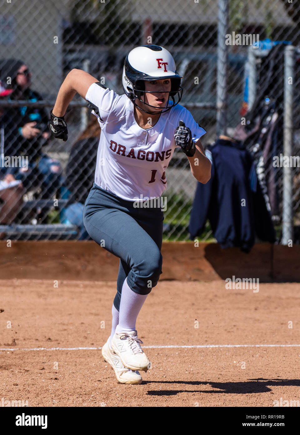 Softball player in white uniform running full speed to first base ...