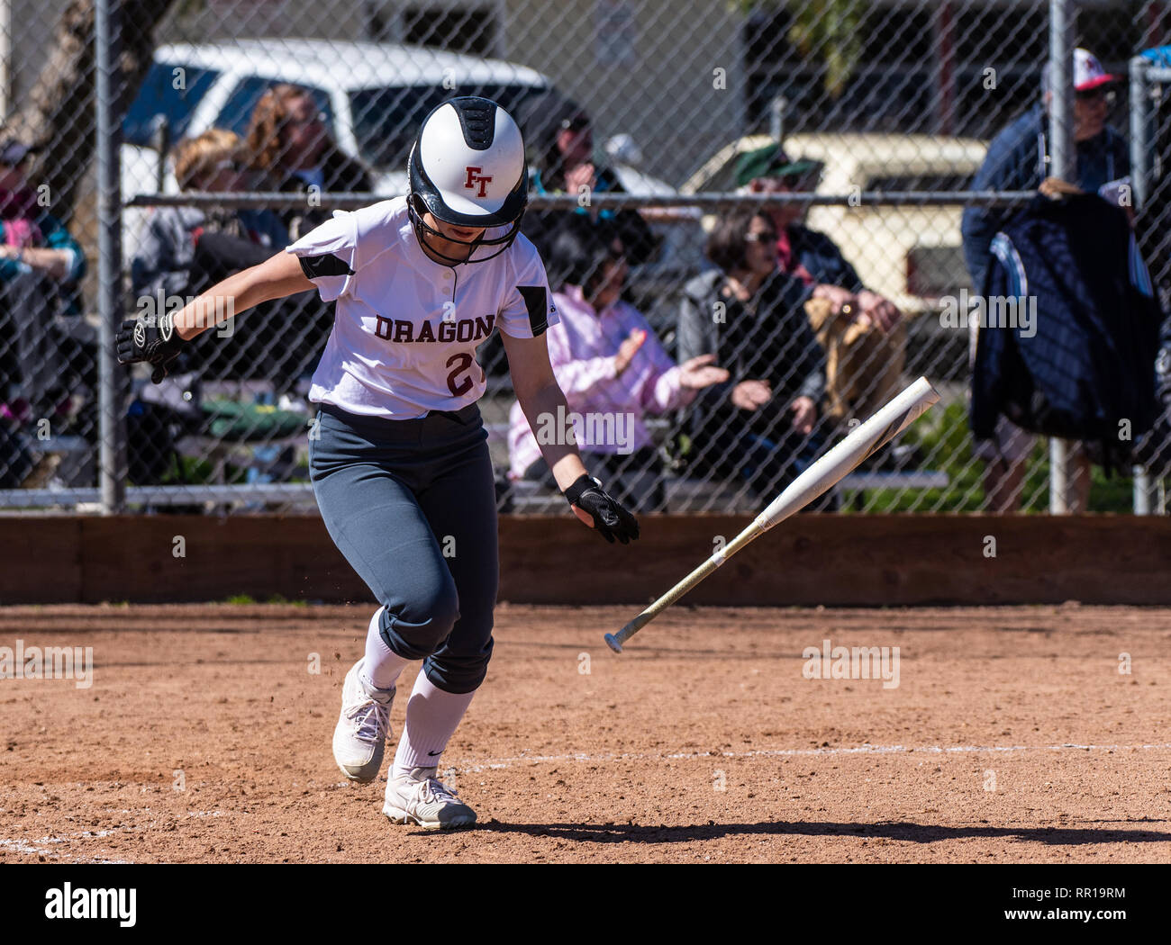 Softball player in white uniform running full speed while flinging bat ...