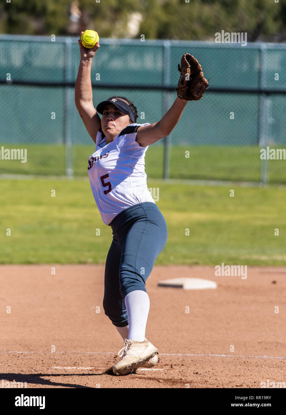 Softball player in white uniform in midpoint of wind up during right ...